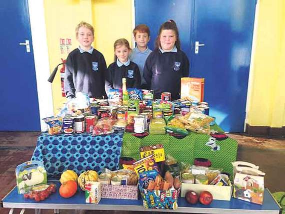 Pupils at Ysgol Padarn Sant with their collection of harvest goods ...
